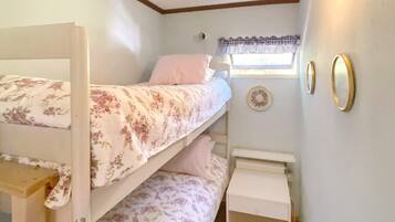 Quarto com beliche, janela, mesinha e decorações nas paredes.