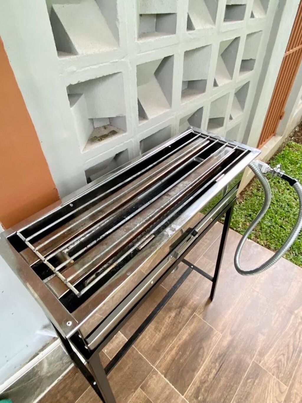 Um banco de metal com uma mangueira acoplada, localizado em um pátio com piso de azulejos.