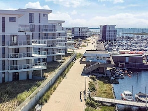 Zona residencial à beira-mar, com edifícios modernos, um porto de iates e uma passarela para pedestres.