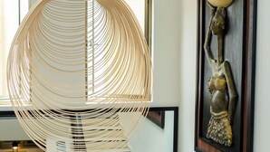 Um interior moderno com um grande candeeiro circular de fibra e uma obra de arte emoldurada na parede.