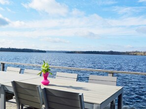 Um deck de madeira com mesa e cadeiras, com vista para um corpo de água.