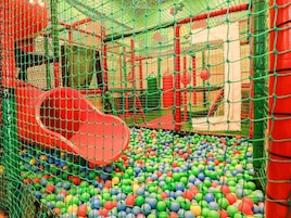 Uma área de recreação com um escorrega vermelho e uma piscina de bolinhas cheia de bolas coloridas.