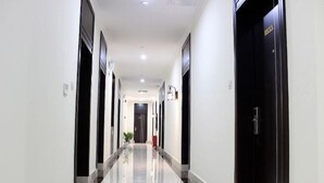Um corredor longo e estreito, com portas de ambos os lados, que leva a um quarto no final.