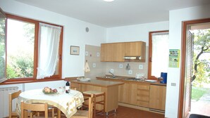 Uma cozinha com armários de madeira, uma mesa de jantar com cadeiras e uma janela com cortinas.