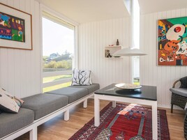 Quarto com um banco, uma mesa, um tapete e obras de arte nas paredes.