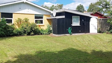 Uma casa de dois andares com garagem, antena parabólica e um gramado bem cuidado.