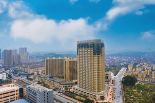 Um edifício alto com vários andares, cercado por outros edifícios e um céu limpo.