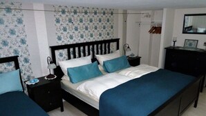 Quarto com uma cama de casal, duas mesas de cabeceira, cômoda e espelho.
