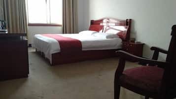 Quarto com cama, mesa de cabeceira de madeira, uma cadeira e janela com cortinas.