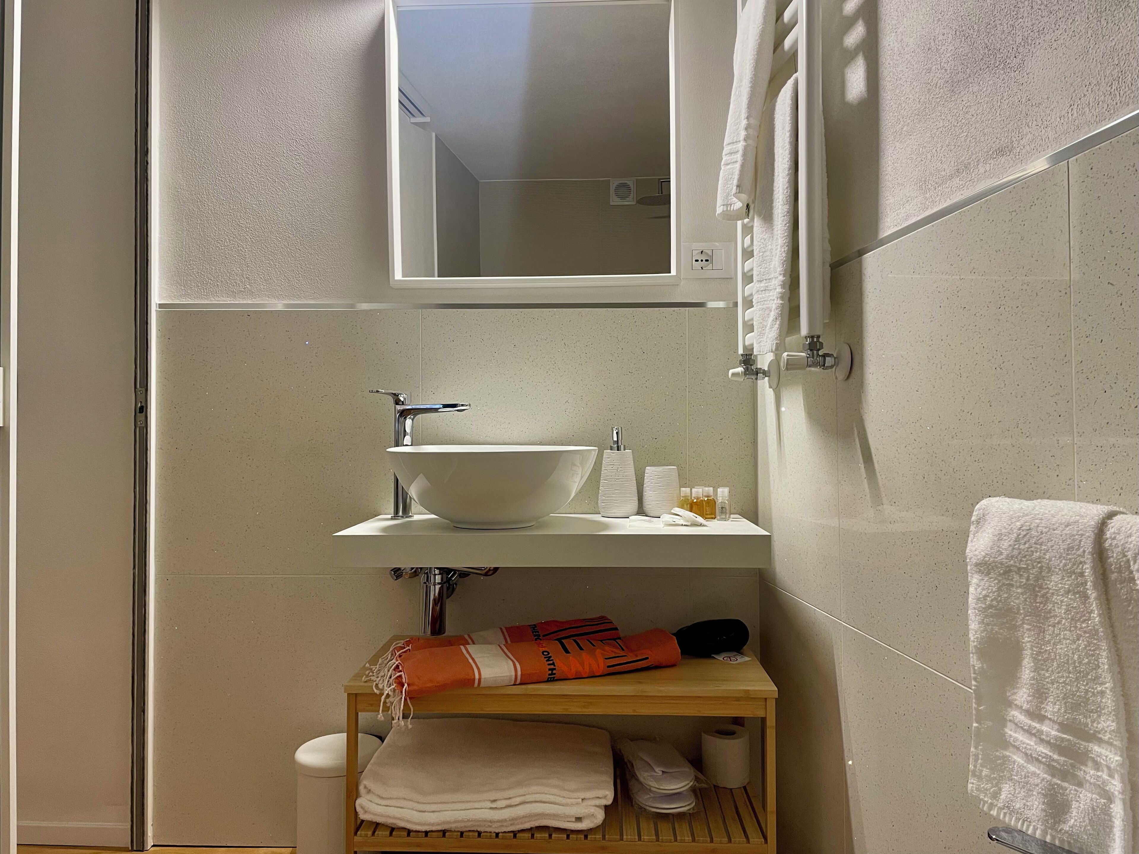 Casa de banho com lavatório branco, espelho e porta-toalhas.