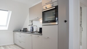 Uma cozinha moderna com forno embutido, máquina de café e chaleira.
