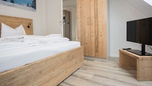 Quarto moderno com cama de madeira, televisão sobre suporte de madeira e pintura na parede.