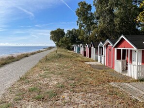 Uma fileira de cabanas de praia com um caminho de brita que leva à praia.