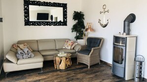 Uma sala de estar com sofá, poltrona, mesa de centro de madeira e lareira.