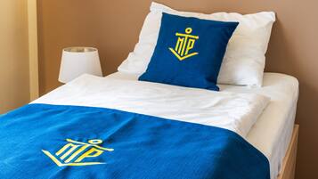 Cama com lençóis brancos e manta azul com um logotipo.