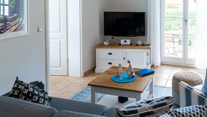 Uma sala de estar com sofá, mesa de centro, televisão e um pequeno armário.