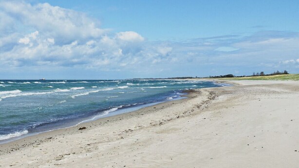 Uma praia com areal e ondas.