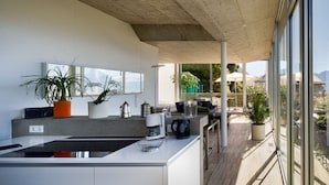 Cozinha moderna com uma ilha grande, área de jantar com assentos externos e janelas amplas com vista para a paisagem ao redor.