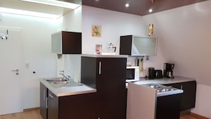 Cozinha compacta com armários escuros, micro-ondas e cafeteira.
