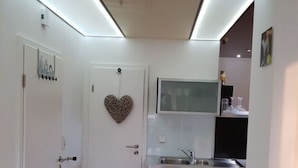 Cozinha compacta com micro-ondas embutido, pia e bancada pequena.