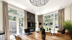 Uma sala de jantar ampla com uma mesa de madeira, cadeiras e uma televisão fixada numa parede de tijolos.