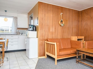 Um espaço de estar compacto com cozinha compacta, parede de madeira, sofá e mesa de jantar.