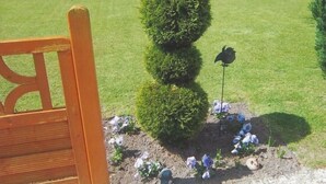 Um jardim bem cuidado, com sebes aparadas, um comedouro de pássaros e uma variedade de flores.