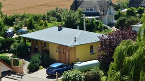 Um bairro residencial com uma casa amarela, um carro azul e um grande reservatório de água.