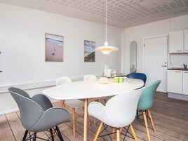 Uma sala de jantar moderna com mesa redonda, cadeiras e um lustre.
