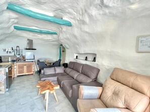 Um interior acolhedor com um sofá seccional, uma área de refeições e uma cozinha com eletrodomésticos modernos.