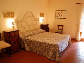Quarto com cama, mesas de cabeceira, uma cadeira e obras de arte nas paredes.