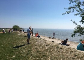 Uma praia com pessoas relaxando e caminhando pela orla.