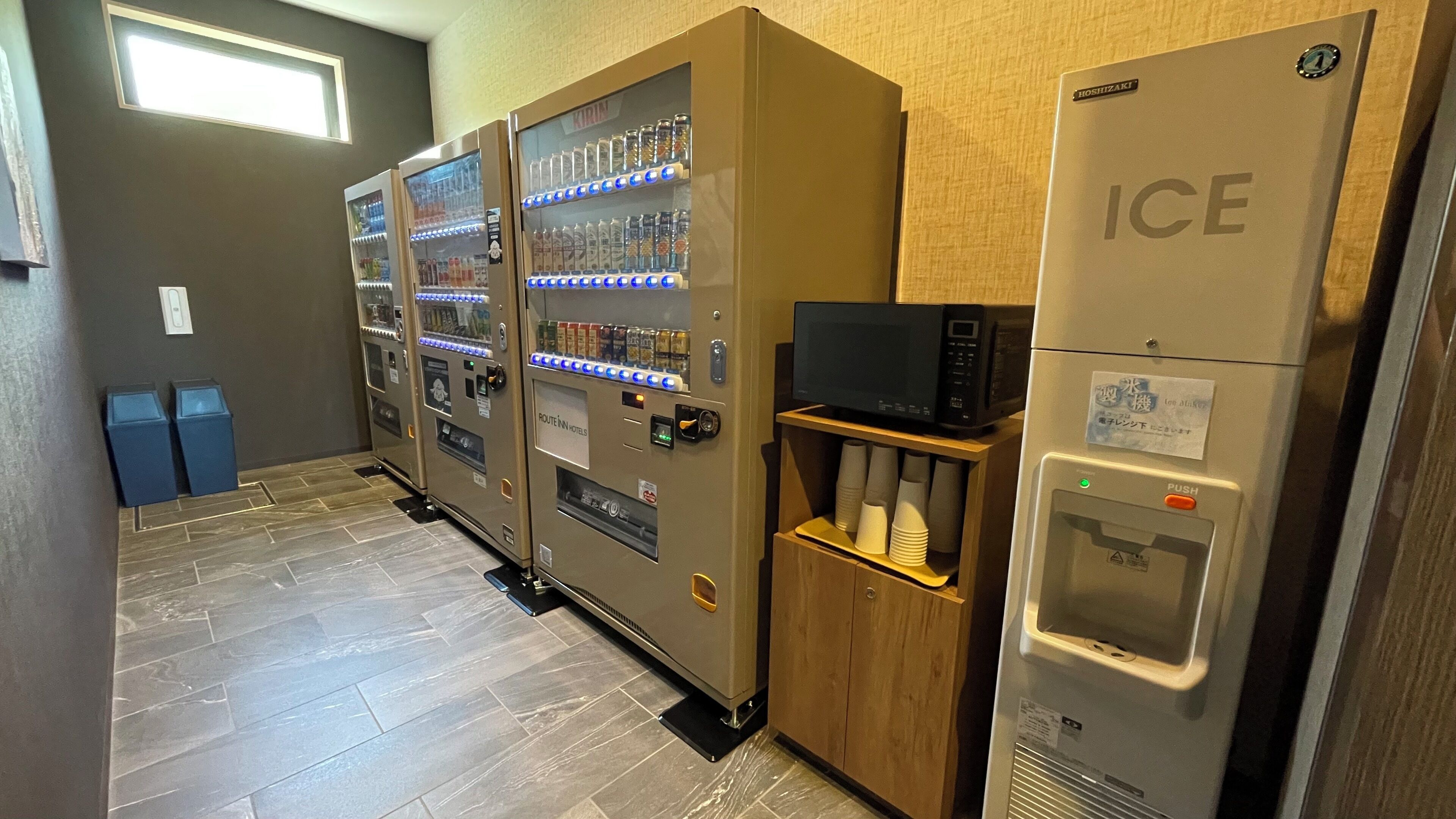 Corredor de hotel com máquinas de venda automática, frigorífico e micro-ondas.