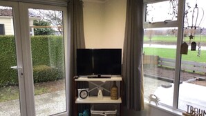 Um quarto com uma televisão em um suporte, um relógio e uma cesta em uma prateleira.