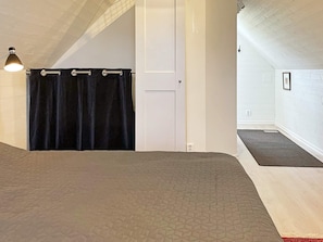 Um quarto com cama, porta, janela e luminária.