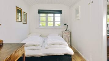 Quarto com cama, escrivaninha, luminária e janela.