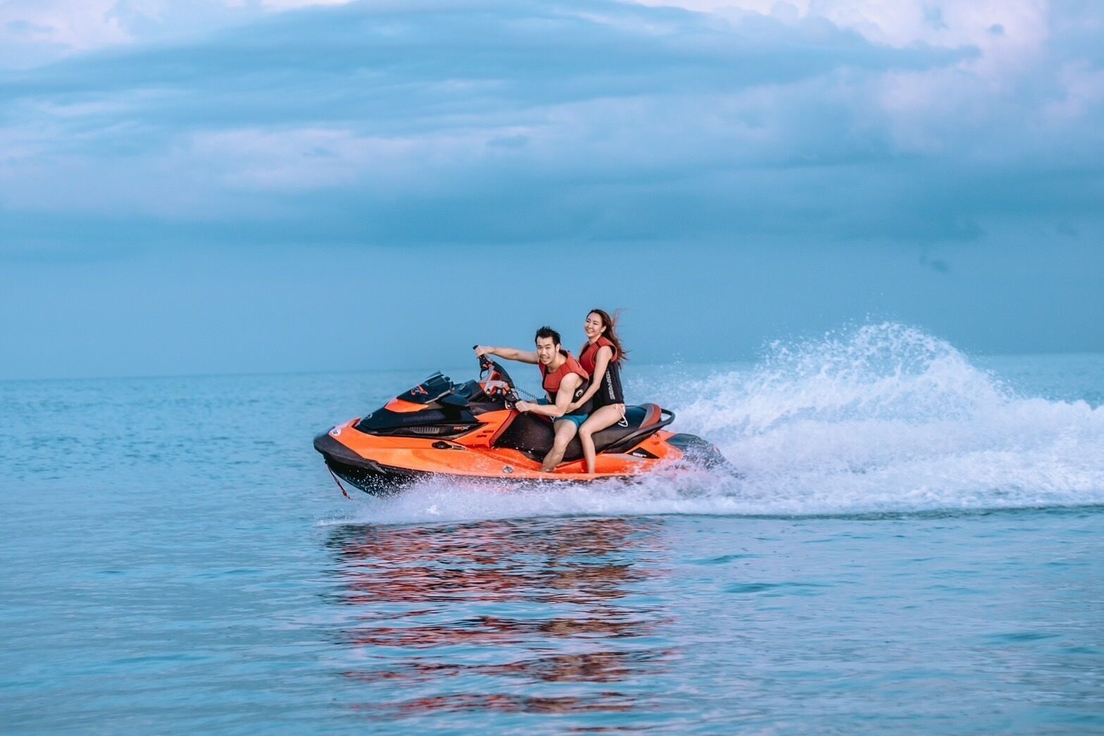 Um jet ski com duas pessoas deslizando por águas calmas.