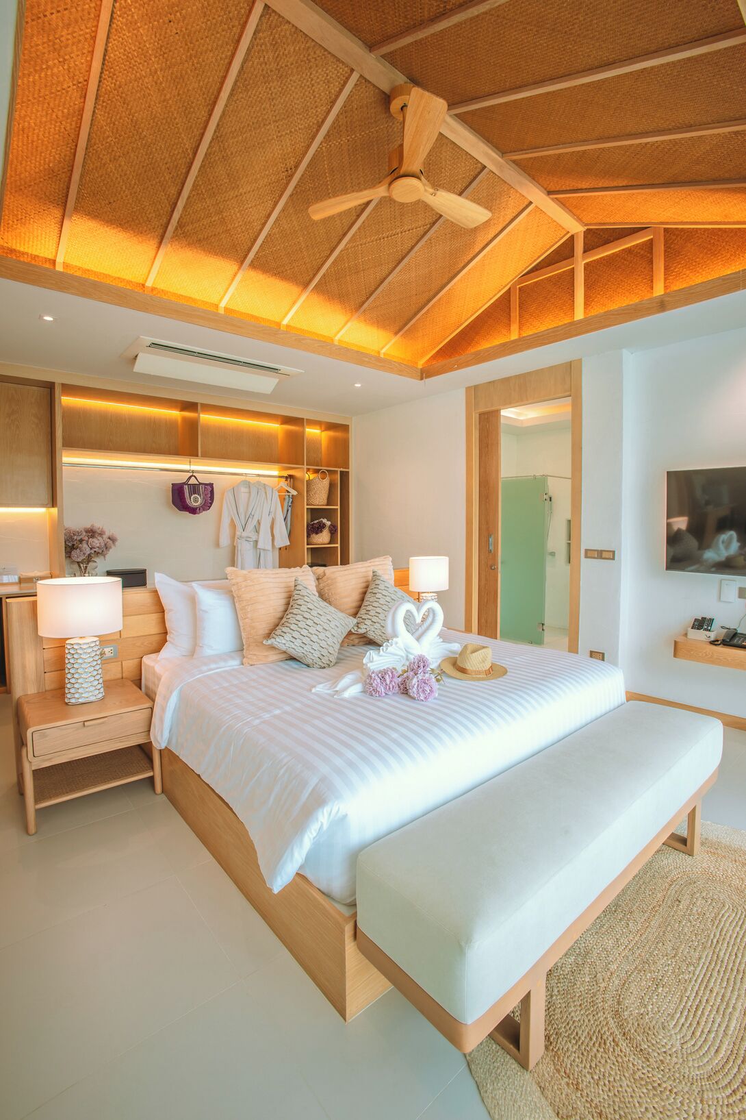 Quarto moderno com uma cama grande, um ventilador de teto de madeira e um guarda-roupa embutido.