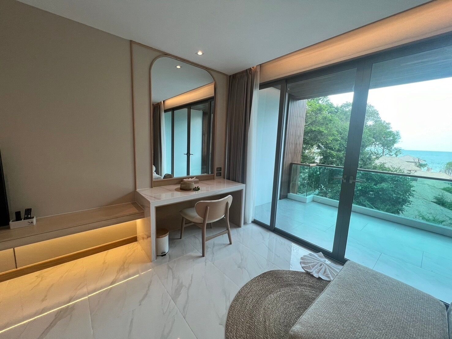 Quarto de hotel moderno com uma varanda ampla, uma escrivaninha com cadeira e uma cama.