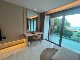 Quarto de hotel moderno com uma varanda ampla, uma escrivaninha com cadeira e uma cama.