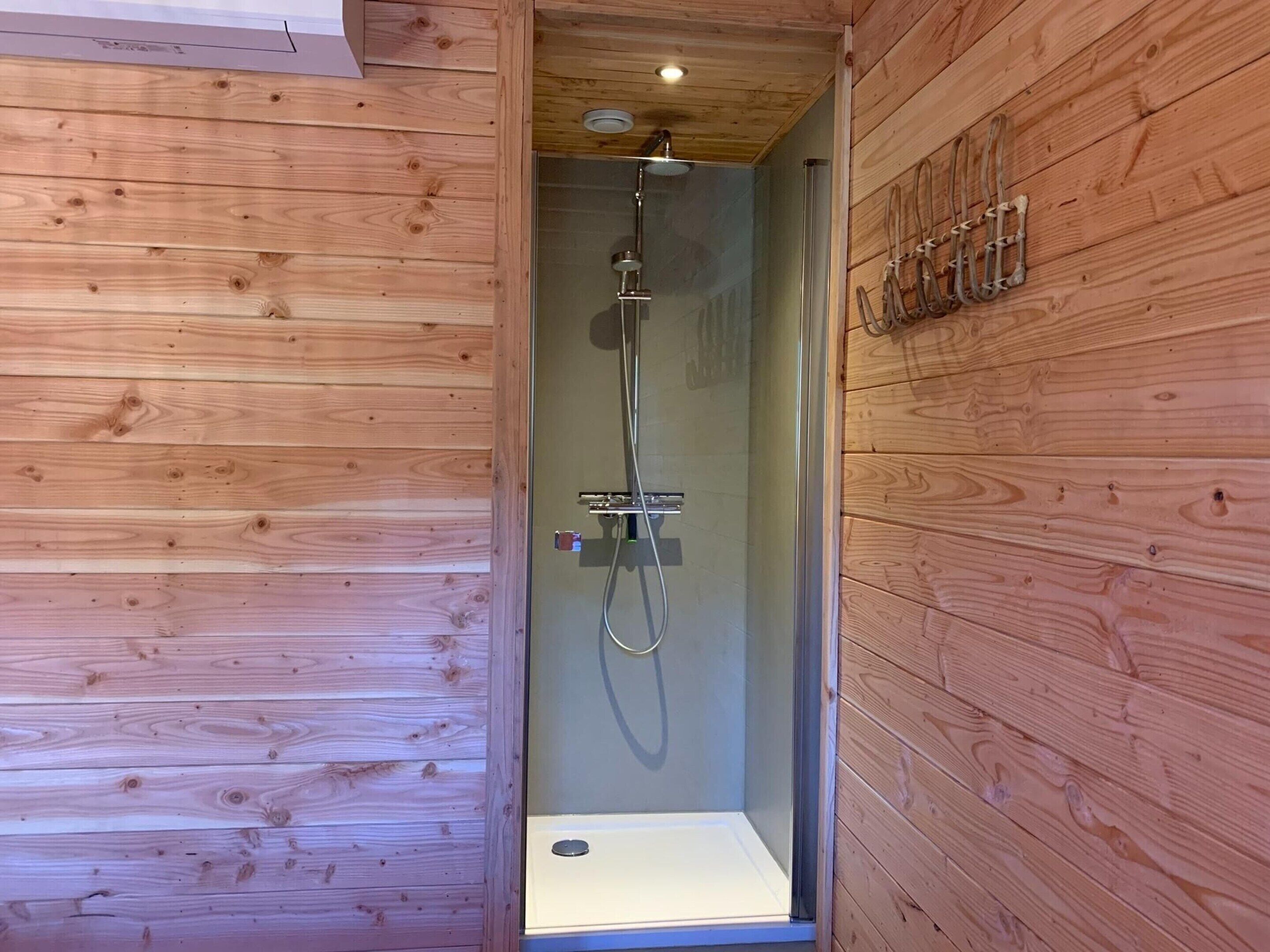Uma cabana de madeira com área de chuveiro em vidro.
