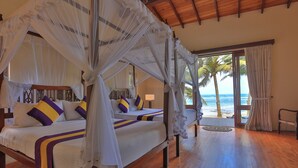 Quarto com duas camas, piso de madeira e vista para a praia.
