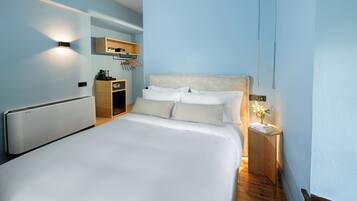 Quarto moderno com uma cama grande, uma mesa de cabeceira com abajur, cômoda de madeira e prateleira na parede.