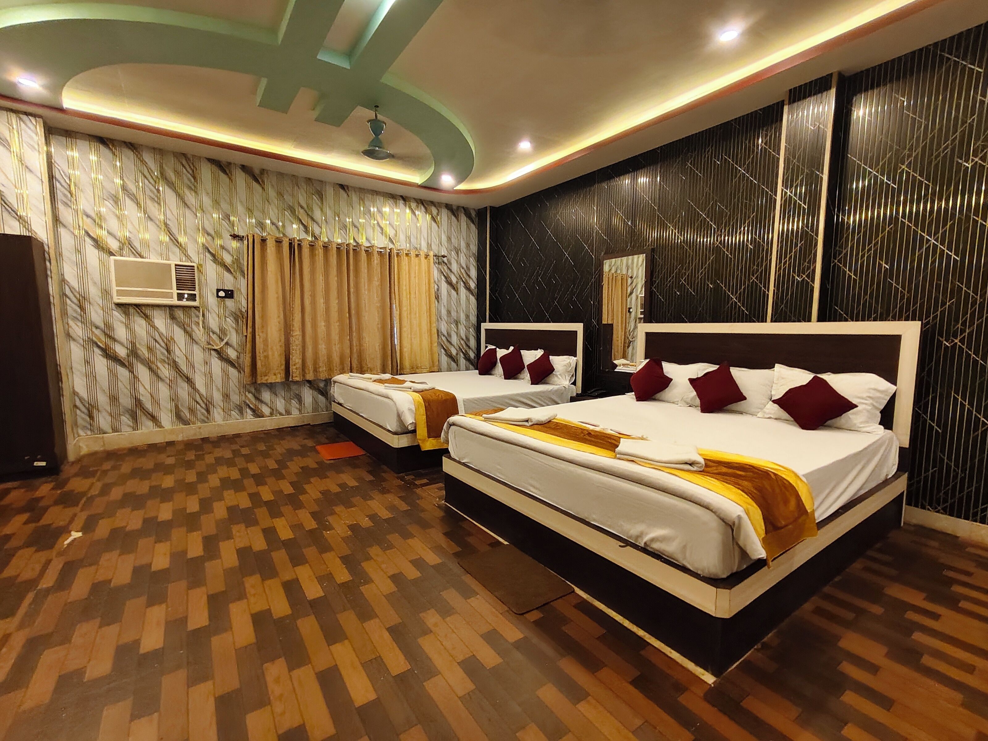 Quarto de hotel com duas camas, um ventilador de teto e um chão estampado.