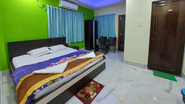 Quarto de hotel com uma cama, um ventilador de teto, ar-condicionado e uma porta.