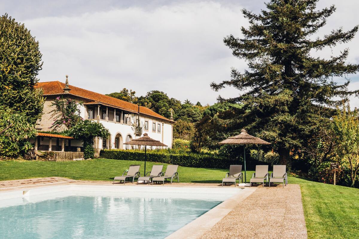 Área de piscina com espreguiçadeiras e um edifício ao fundo.
