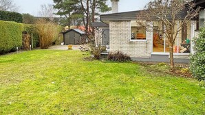 Uma propriedade residencial com gramado bem cuidado, uma casa de tijolos e um pequeno galpão.