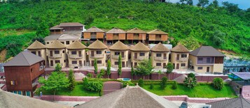 Um resort com vários edifícios, incluindo uma estrutura central com piscina e alguns edifícios menores com telhados de palha.