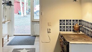 Cozinha com fogão, painel de azulejos e porta que dá para o exterior.