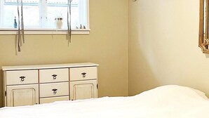 Quarto com cama, cômoda e janela com cortinas.